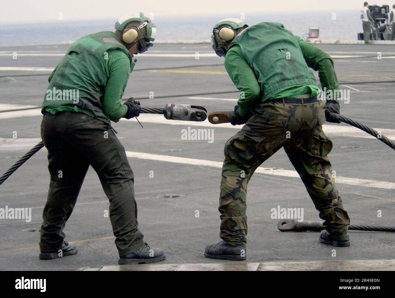 US Navy Flight deck sailors attach a new arresting cable to the ...