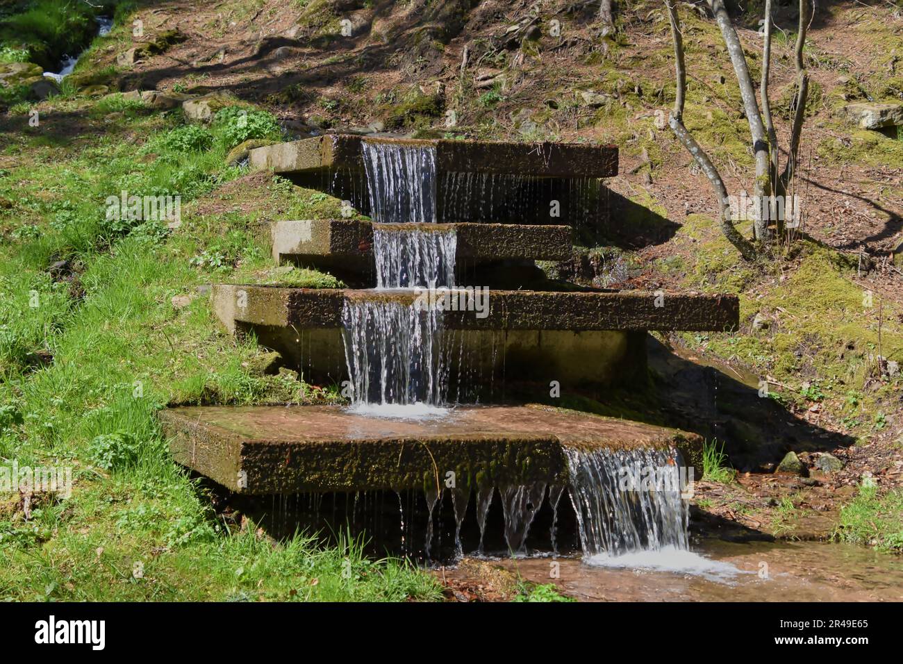 A picturesque waterfall cascading down a set of stairs in front of a ...