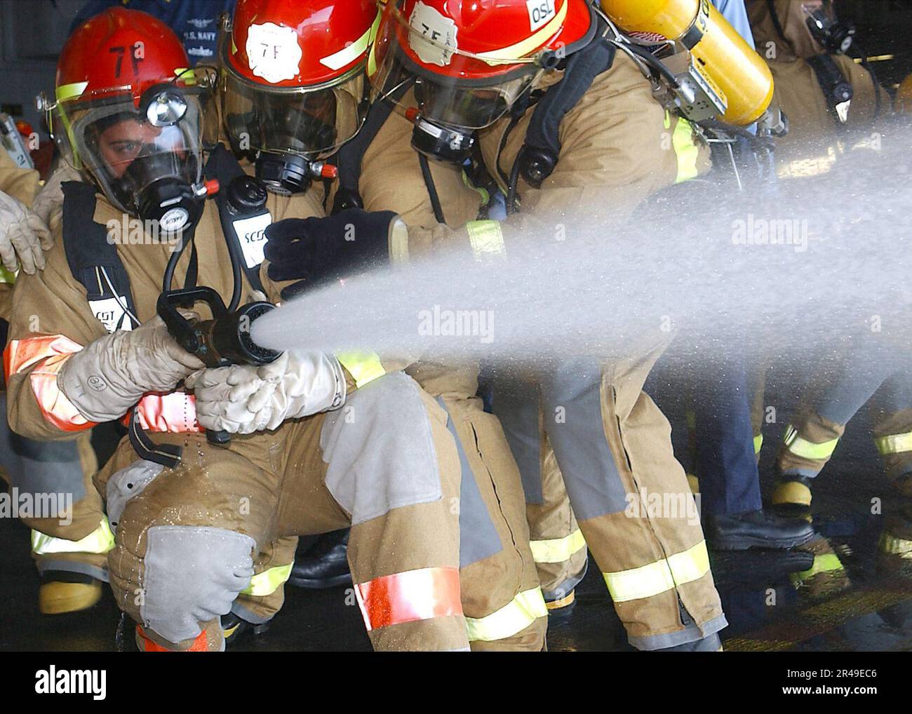 US Navy One of the ship's damage control teams charge a fire hose ...