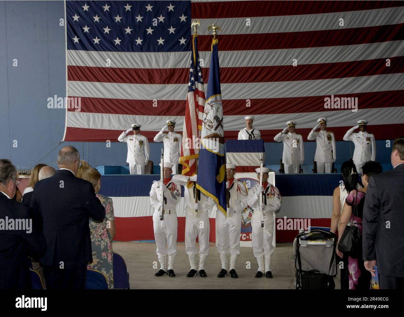 US Navy Honored guests and participants render honors during the singing of the national anthem ...