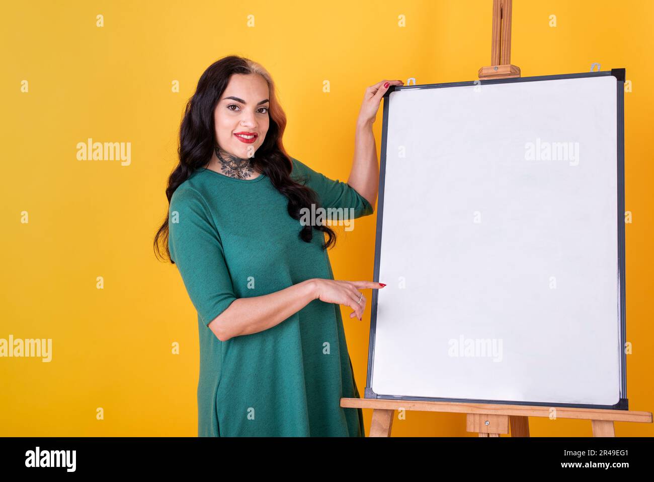 Beautiful woman near a blank whiteboard against a yellow background ...