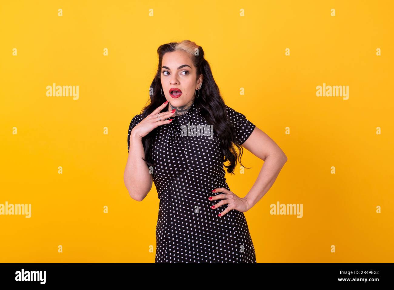 Beautiful pin-up girl posing to the camera over yerllow background ...