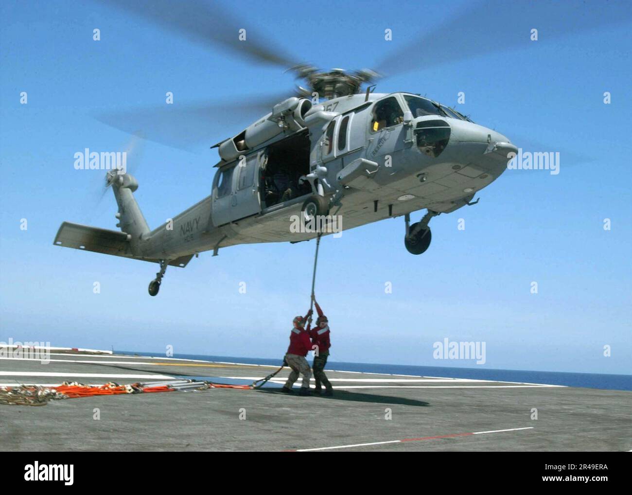 US Navy Personnel secure a cargo net to a MH-60S Knighthawk assigned to Chargers of Helicopter ...