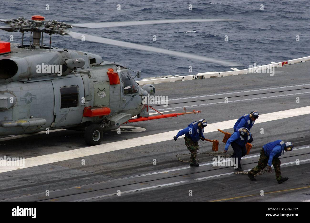 US Navy Four chock and chain handlers dash away from an SH-60B Sea Hawk ...