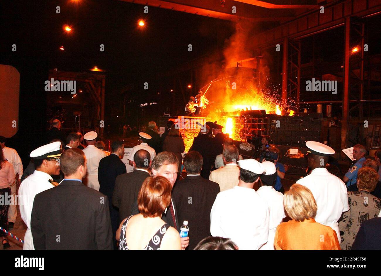 US Navy Workers pour steel into a mold to form the bow stem of the ...