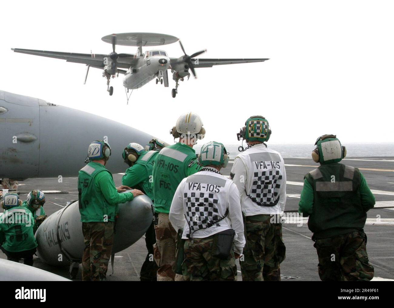 US Navy Aircrew stand ready as an E-2C Hawkeye makes an arrested ...