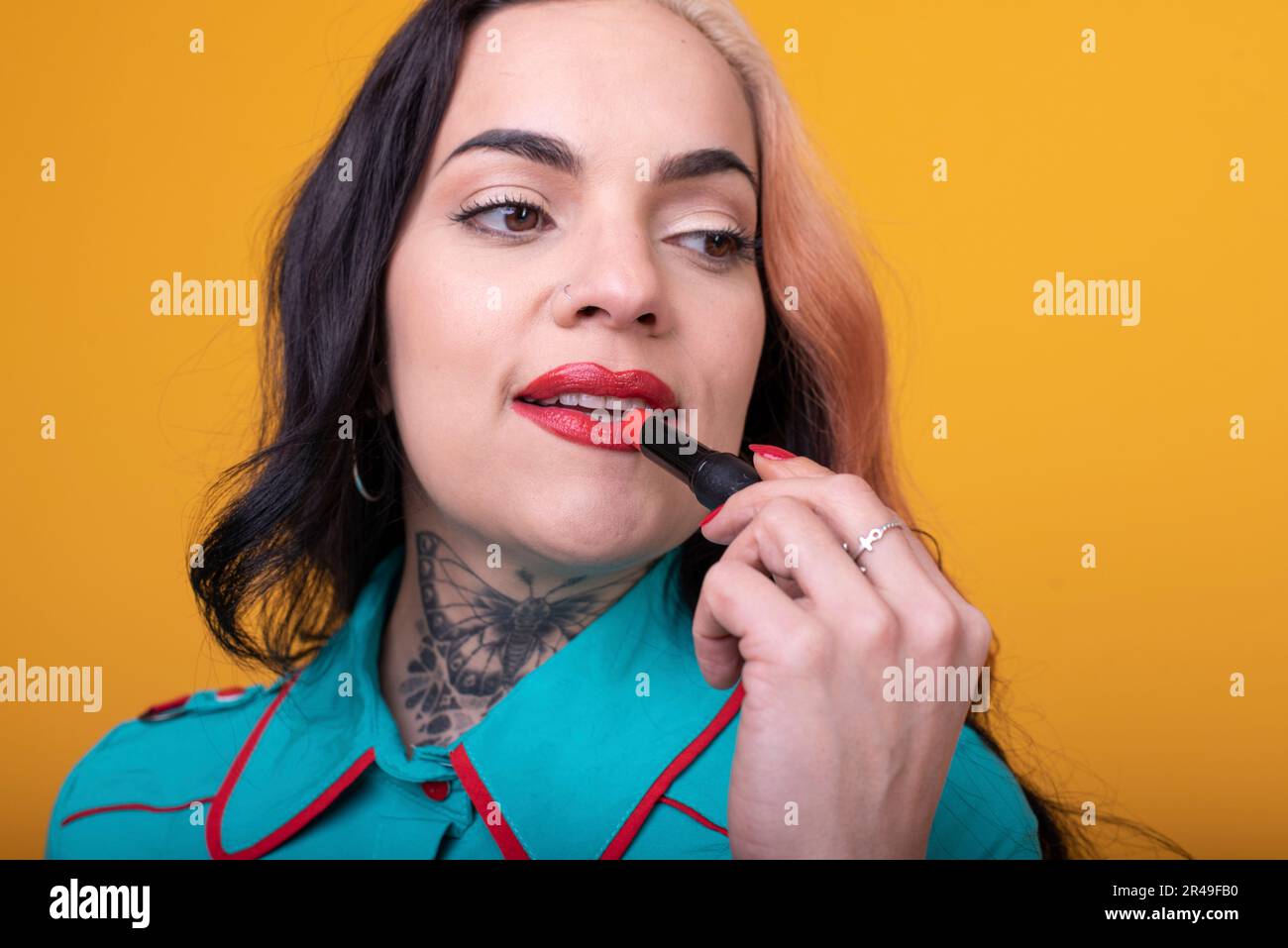 Beautiful Caucasian Woman Applying A Bright Red Color Lipstick On Her Lips Over Yellow