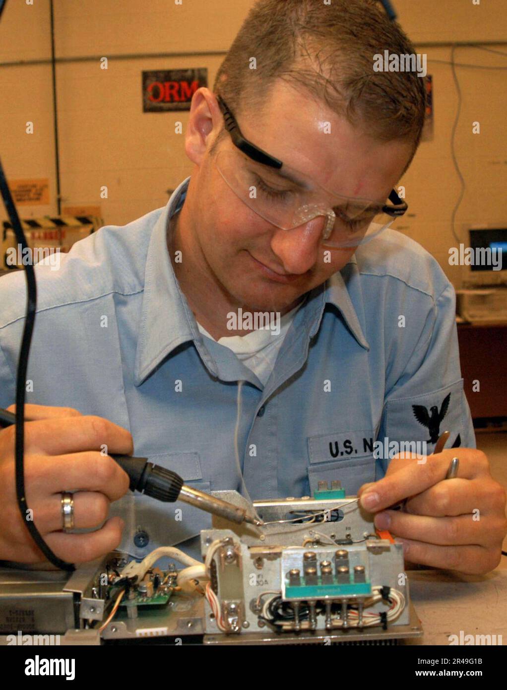 US Navy A Sailor solders a wire to a piece of electrical equipment ...