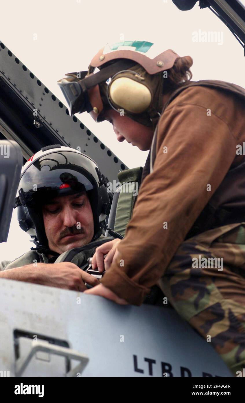 US Navy A squadron crewmember helps strap Photographer's Mate 1st Class ...