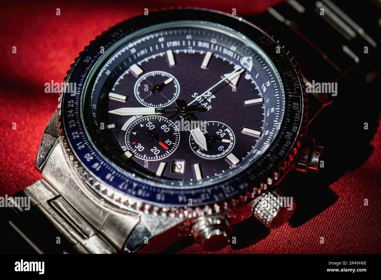 A classic analog wristwatch with a blue face, set against a vivid red ...