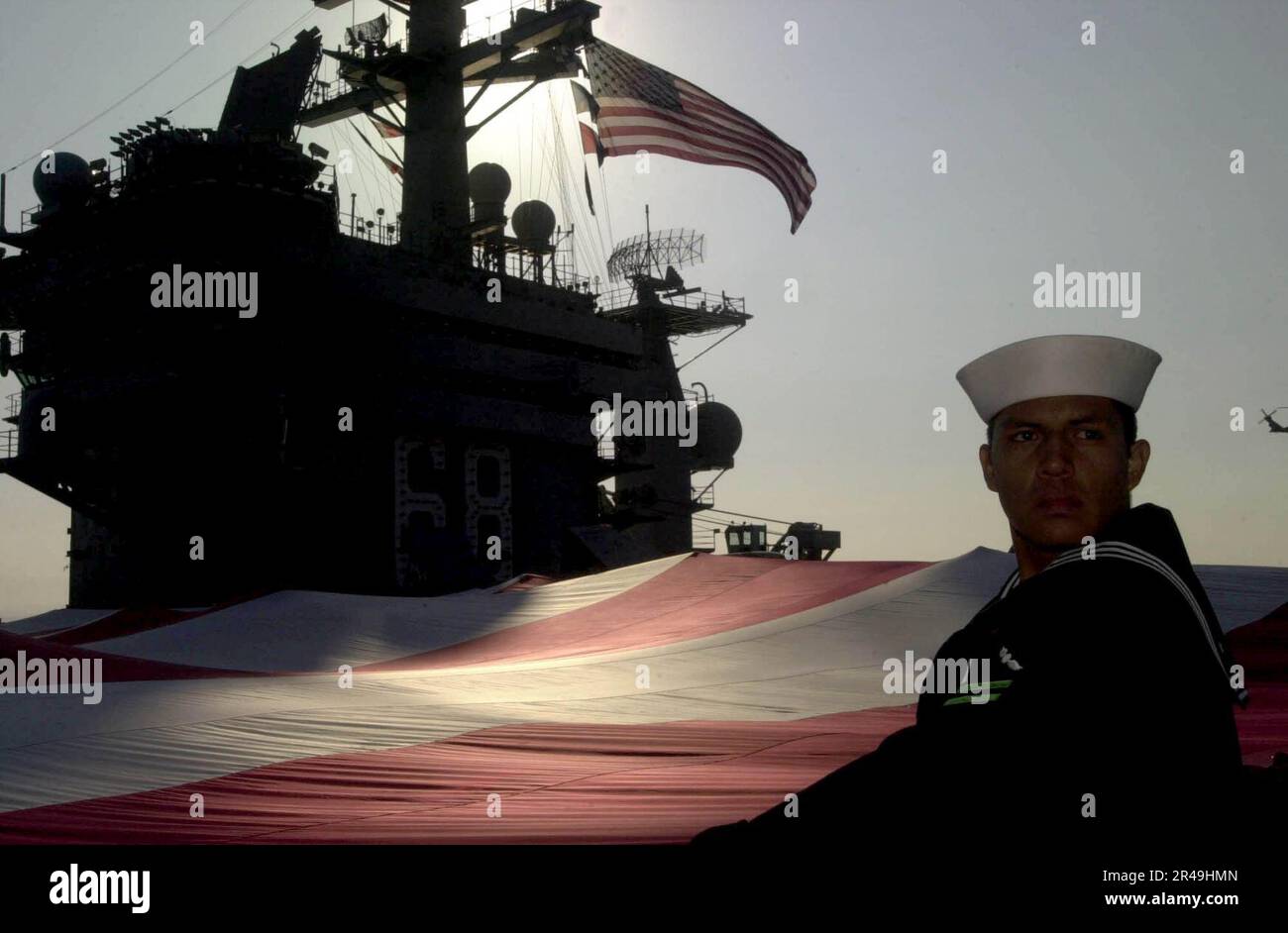 US Navy A Sailor participates in a flag unfurling evolution on the ...