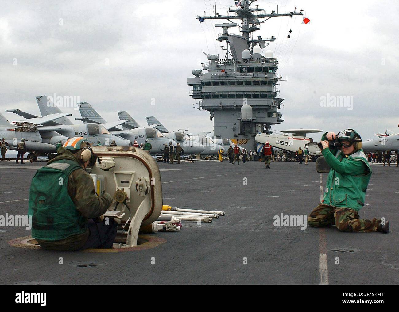 US Navy Photographer's Mate photographs a sailor checking aircraft ...