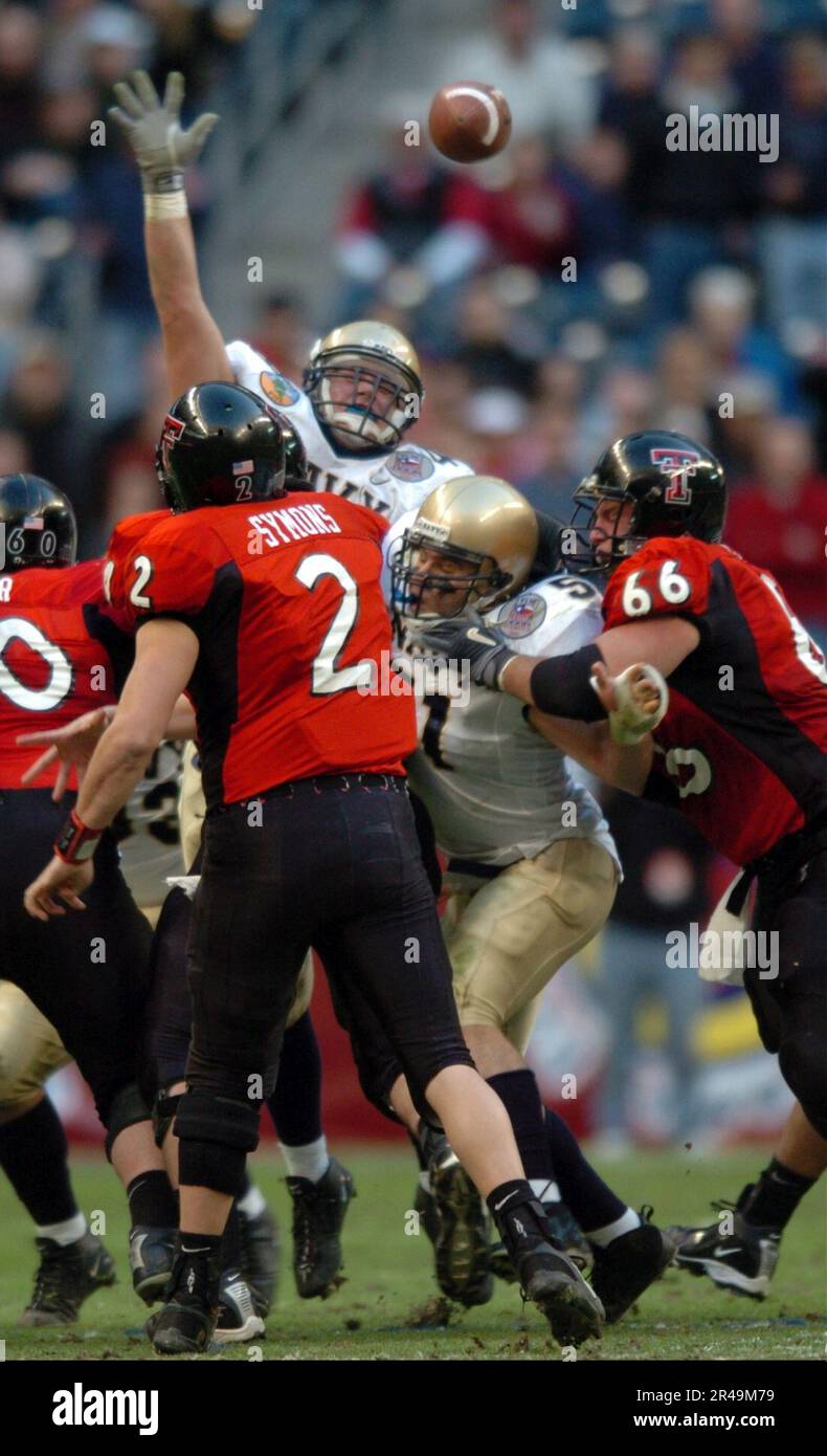 US Navy Texas Tech quarterback passes the ball as Navy linebacker leaps ...