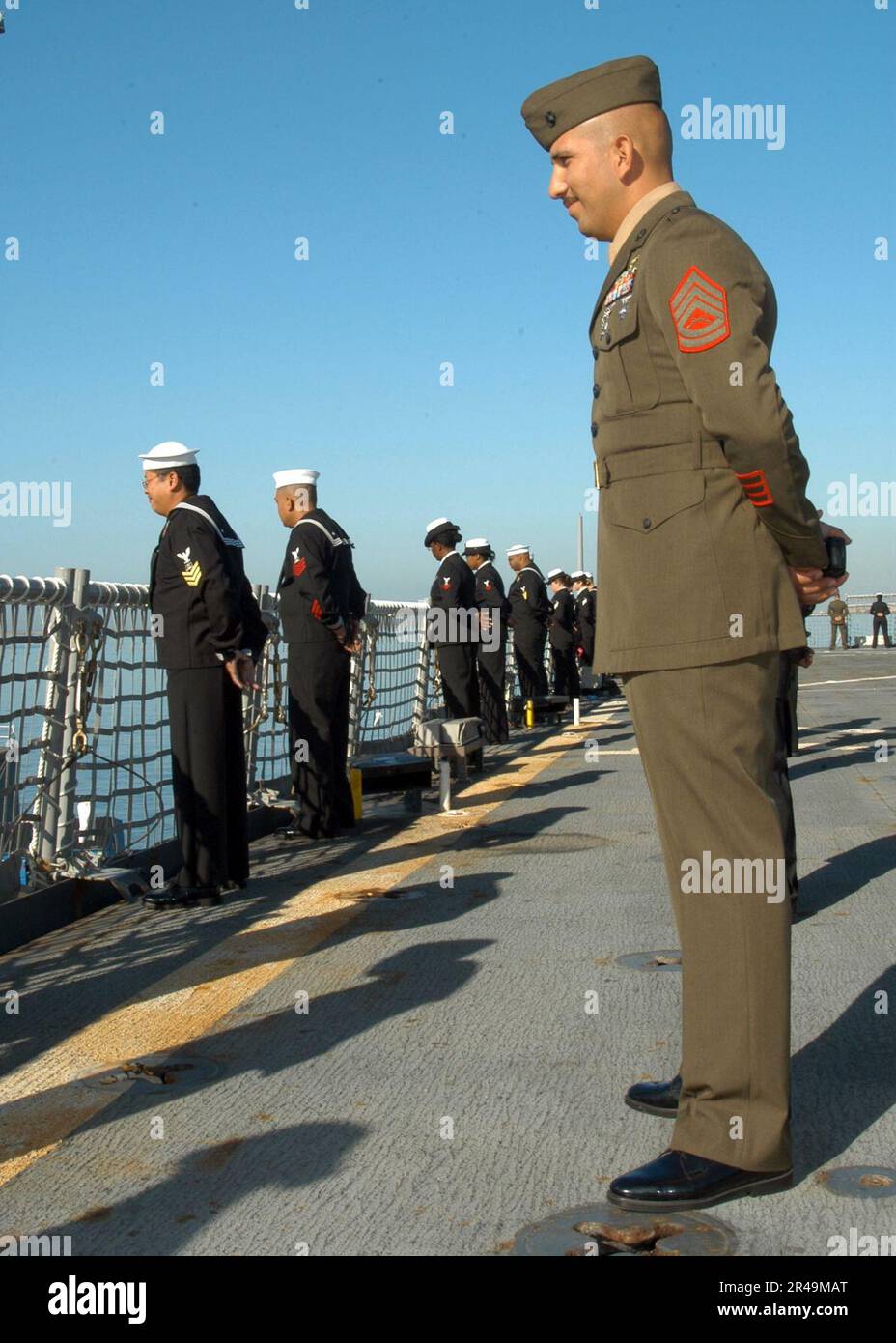 US Navy Gunnery Sgt. looks on as Sailors man the rails on board USS ...