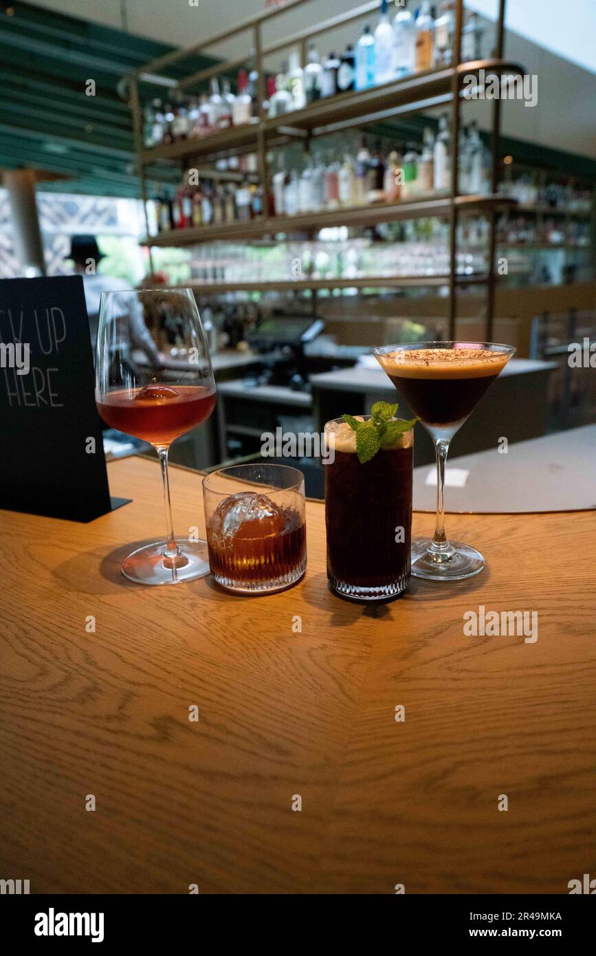 Three glasses of various beverages sit atop a bar counter, ready for ...