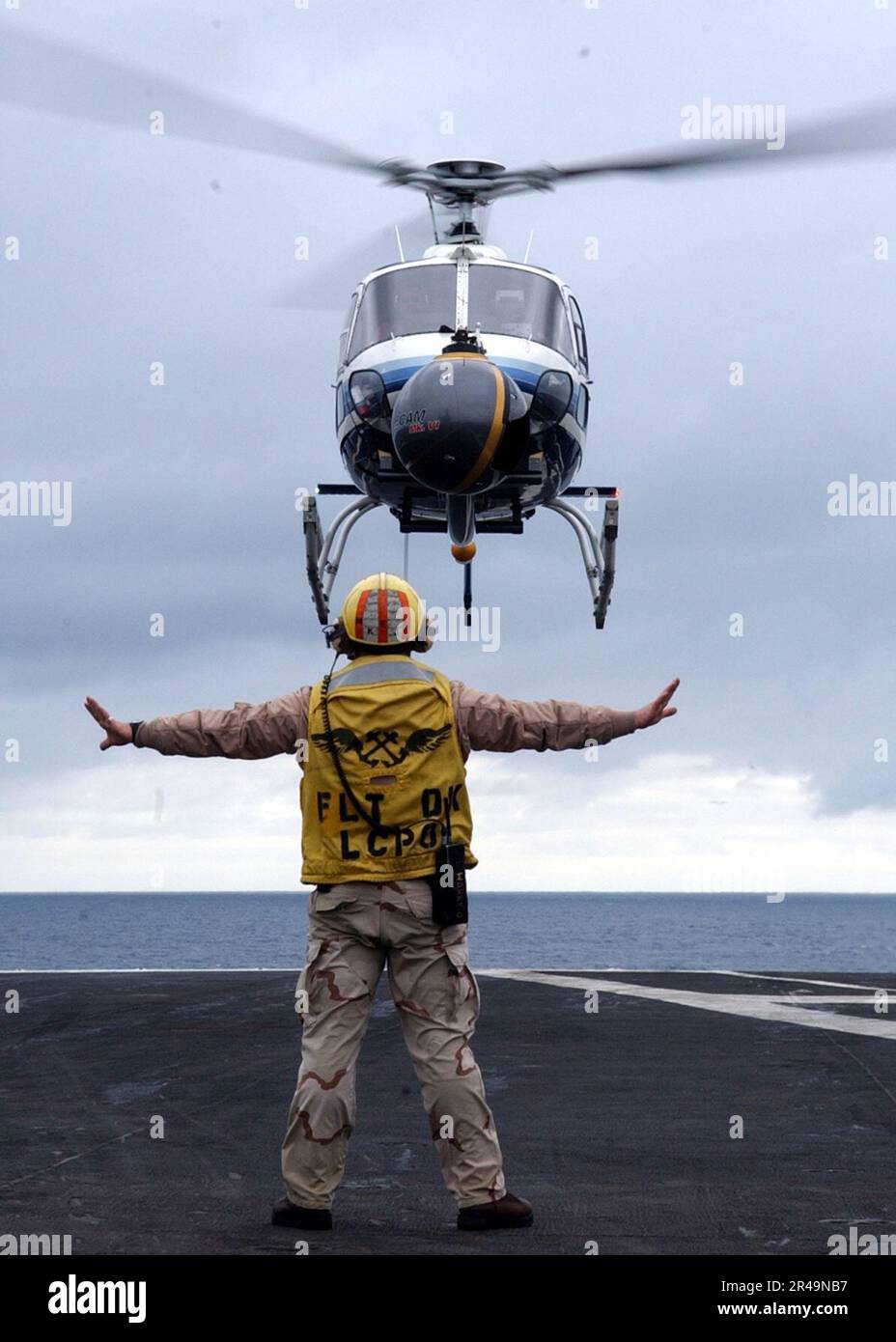 US Navy guides a commercial aerial filming helicopter safely to the flight deck aboard USS Carl ...