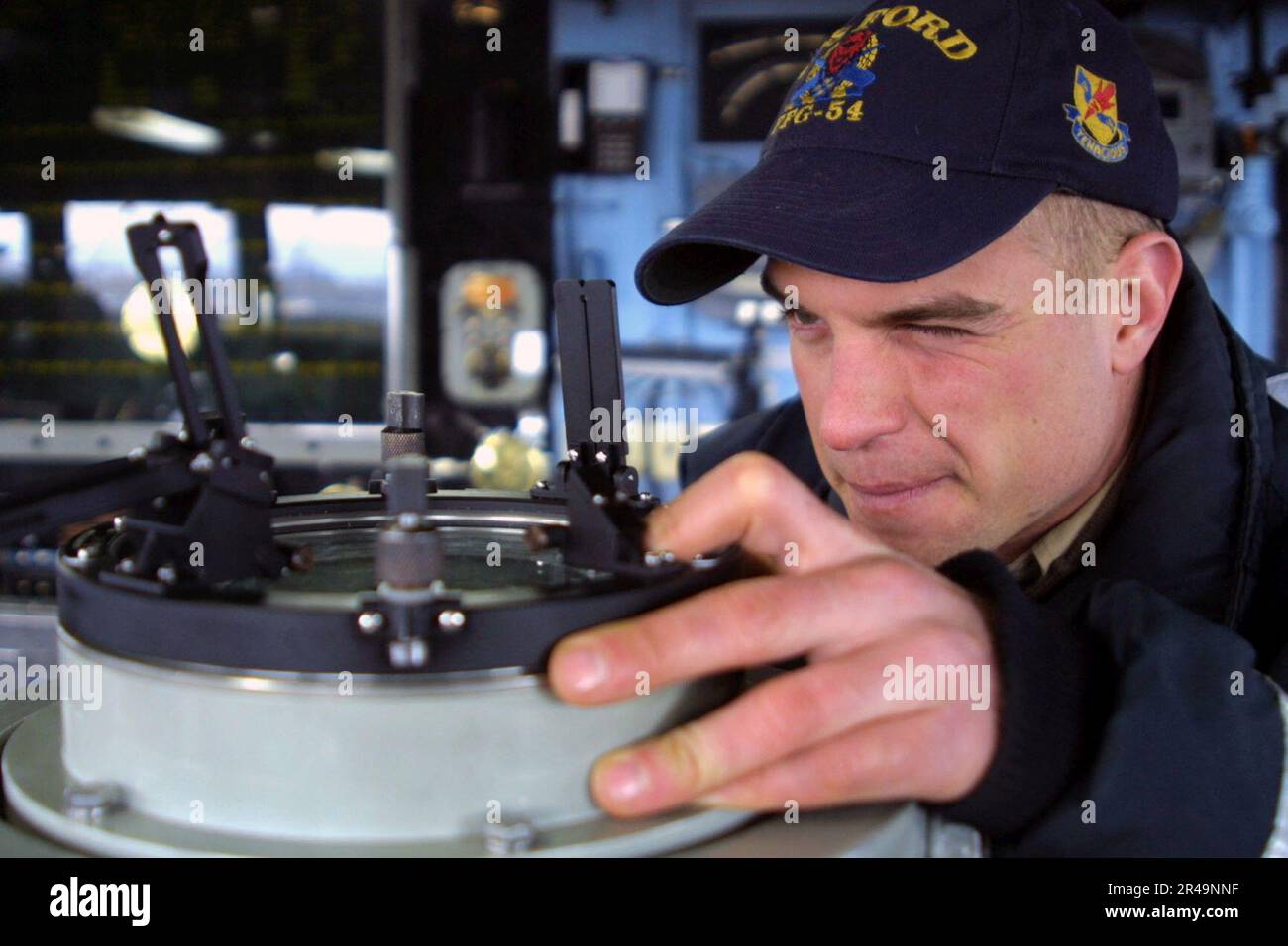 US Navy peers through the alidade on the bridge aboard the guided ...