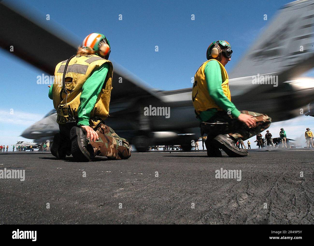 US Navy Flight deck catapult crew members work the ship's flight deck ...