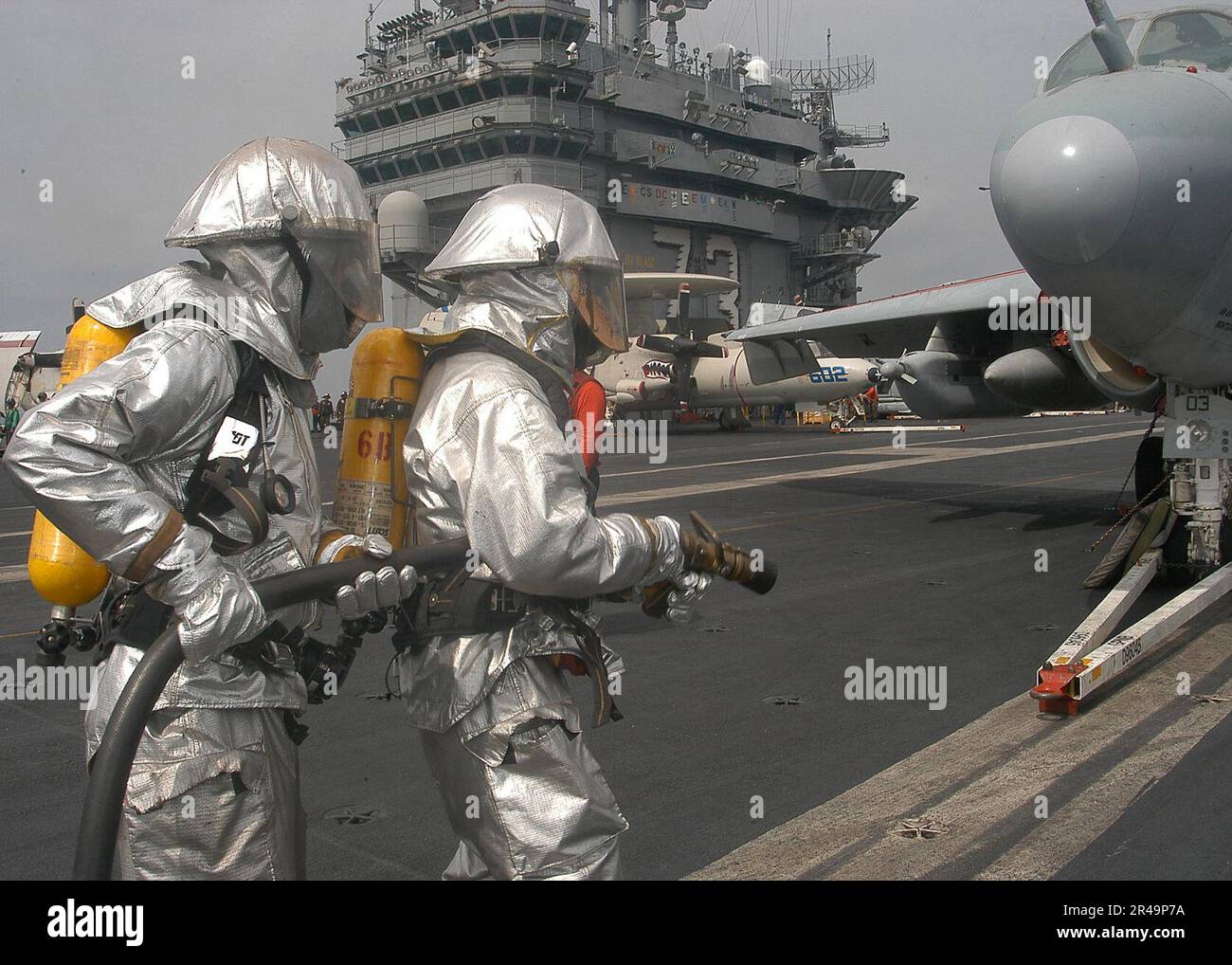 US Navy Sailors assigned to flight deck fire fighting approach an ...