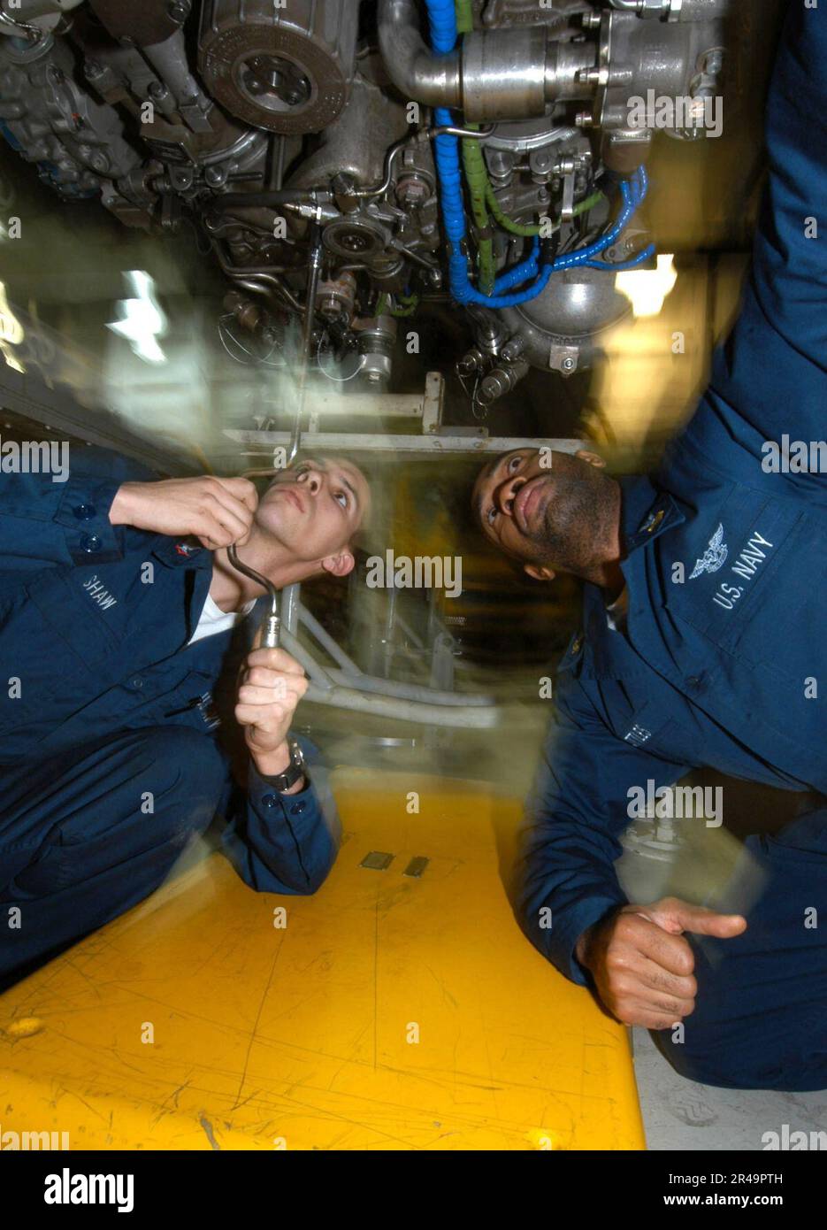 US Navy Aviation Machinist's Mates install a drain on an F-A-18C Hornet ...