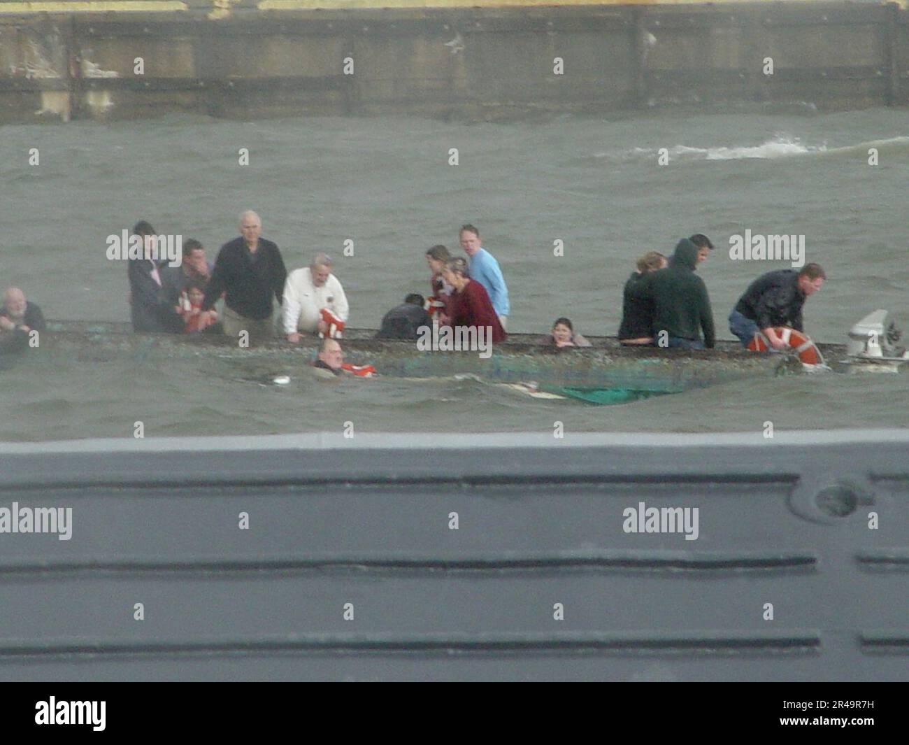 US Navy Passengers of the water-taxi cling to the hull of the capsized ...