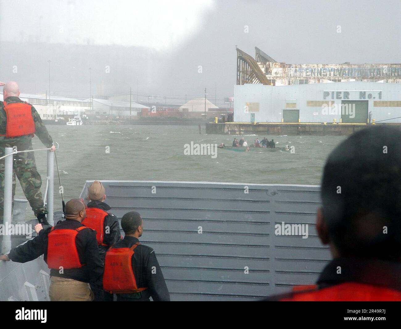 US Navy Passengers of the water-taxi cling to the hull of the capsized ...