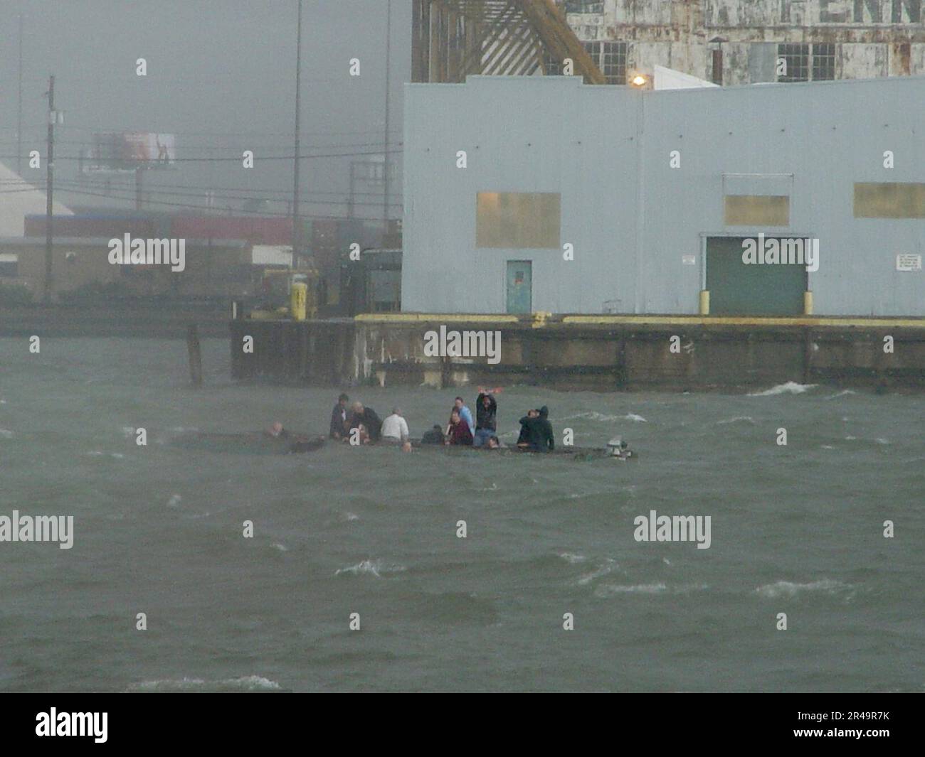 US Navy Passengers of the water-taxi cling to the hull of the capsized ...