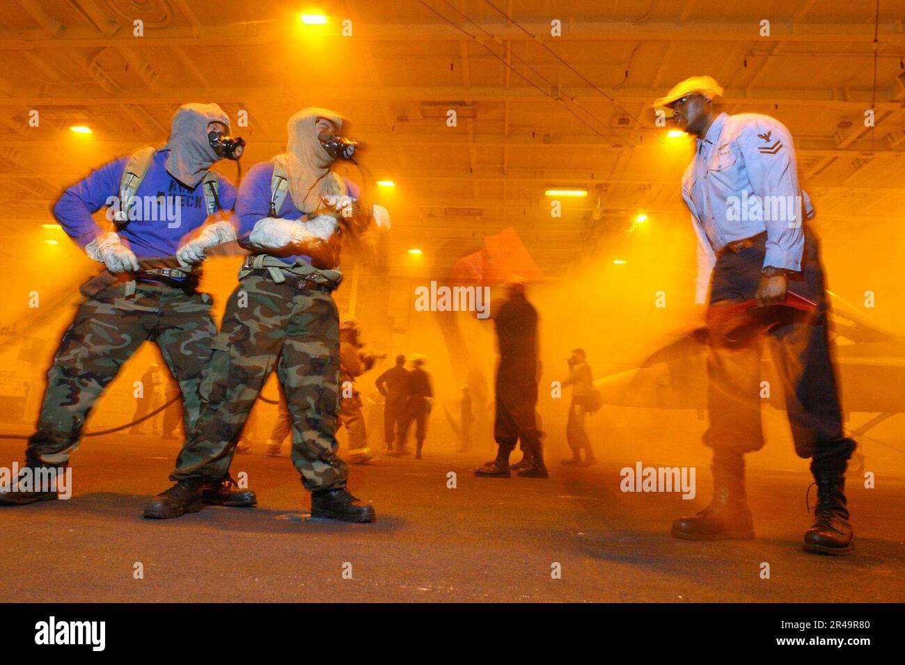 US Navy Sailors assigned to a firefighting hose team aggressively ...
