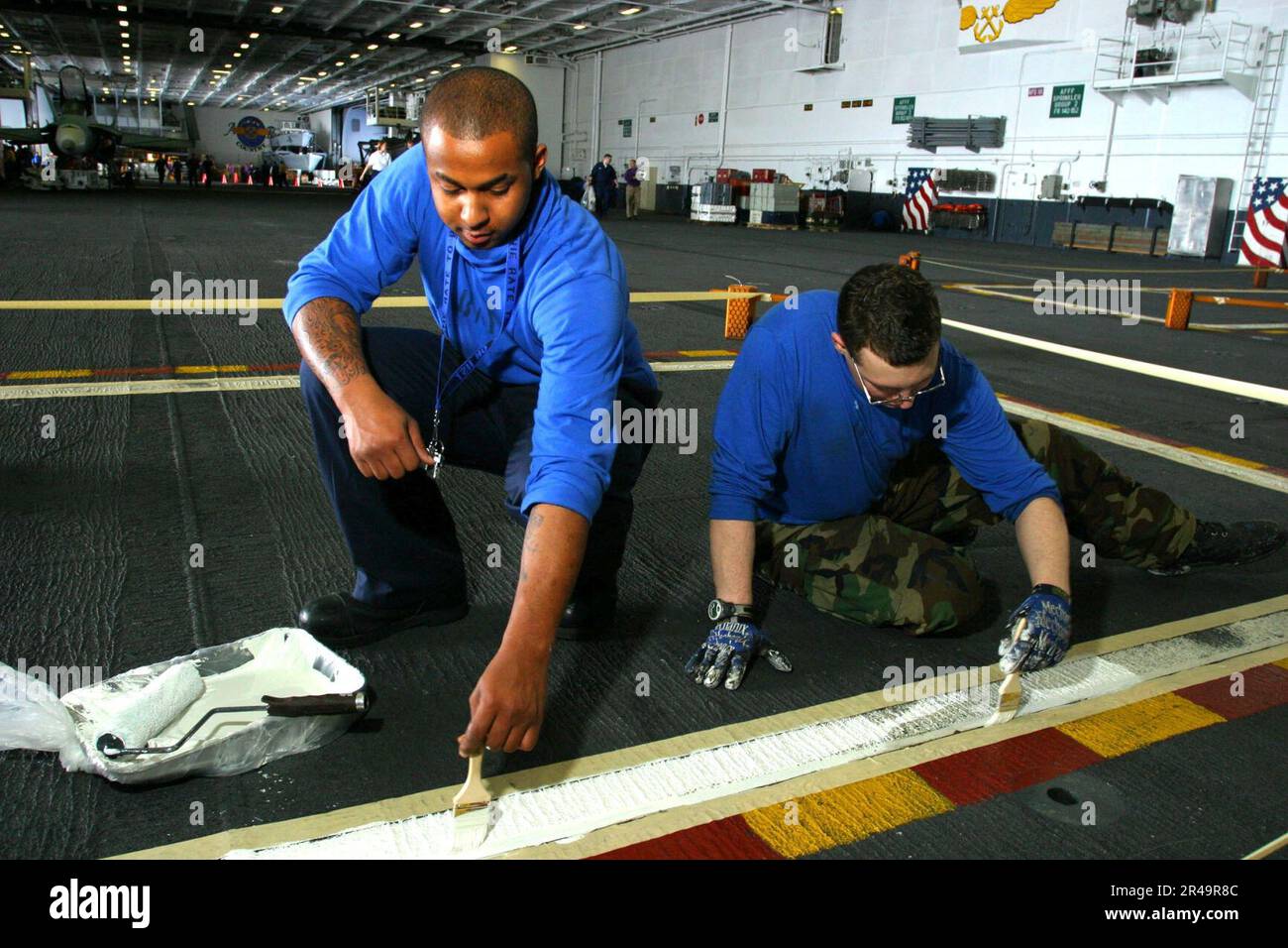US Navy Airman apply touch-up paint to the warning markings surrounding ...