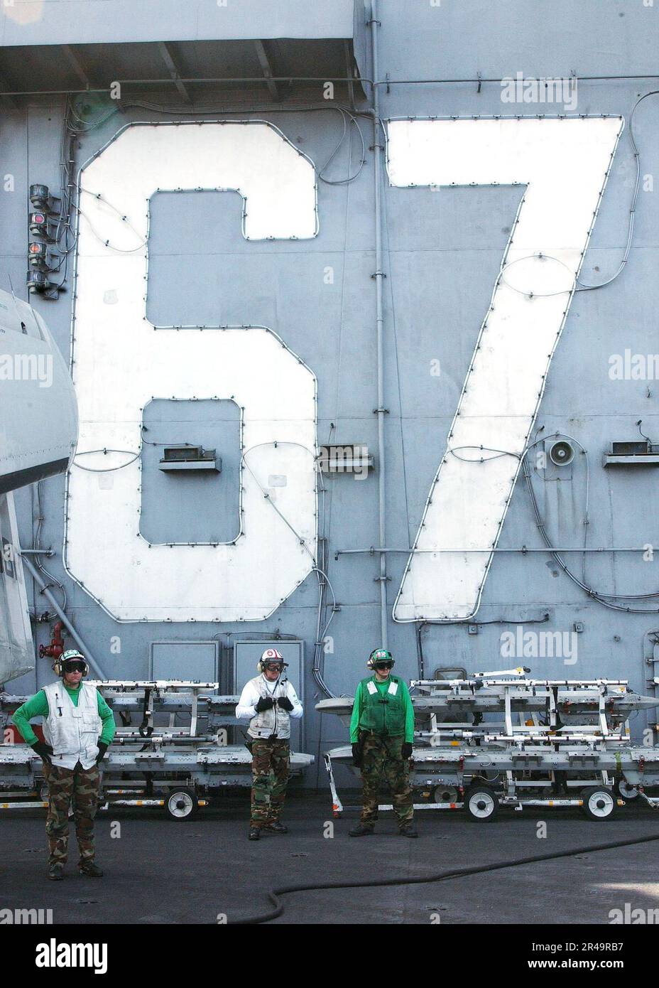 US Navy Sailors observe flight operations while standing in front of ...