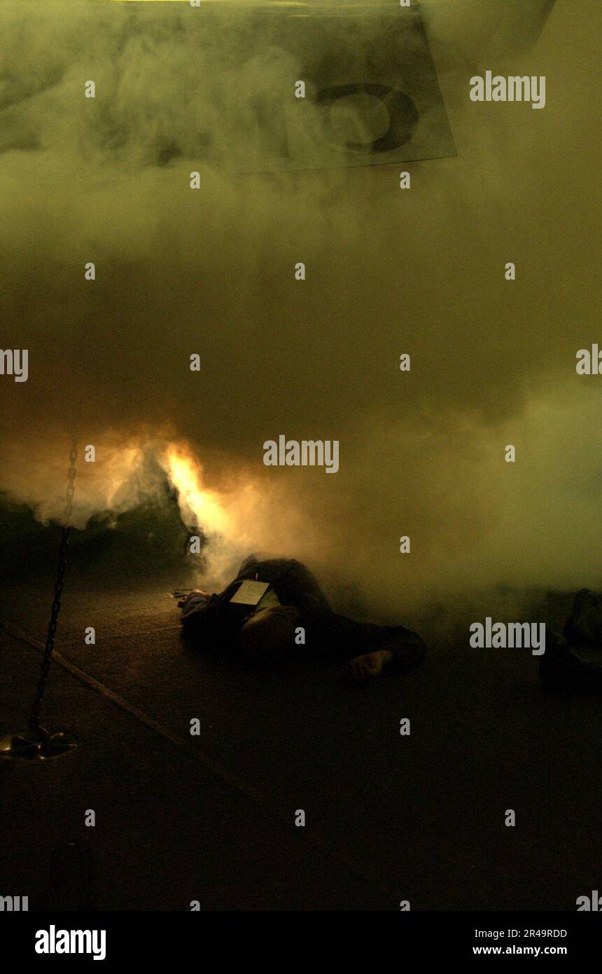 US Navy Simulated smoke pours over a sailor as he plays the role of a ...