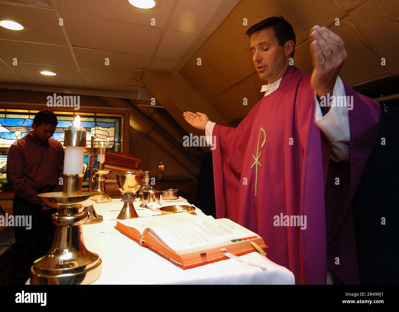 US Navy Navy Chaplain, reads a prayer during a church service in the ...
