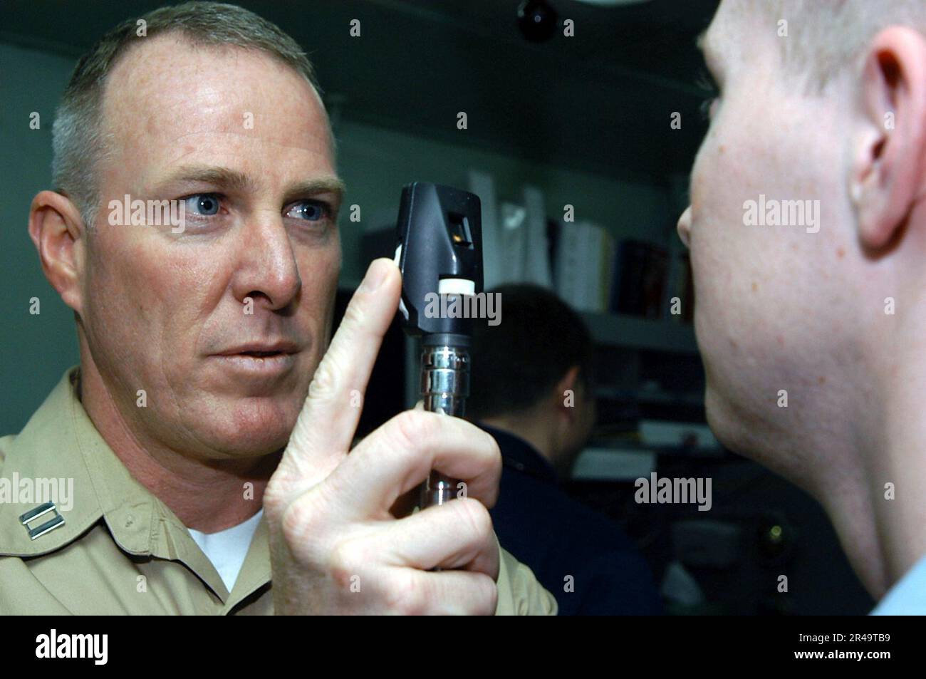 US Navy Lt. examines a patient's eyes in the Medical Department aboard ...