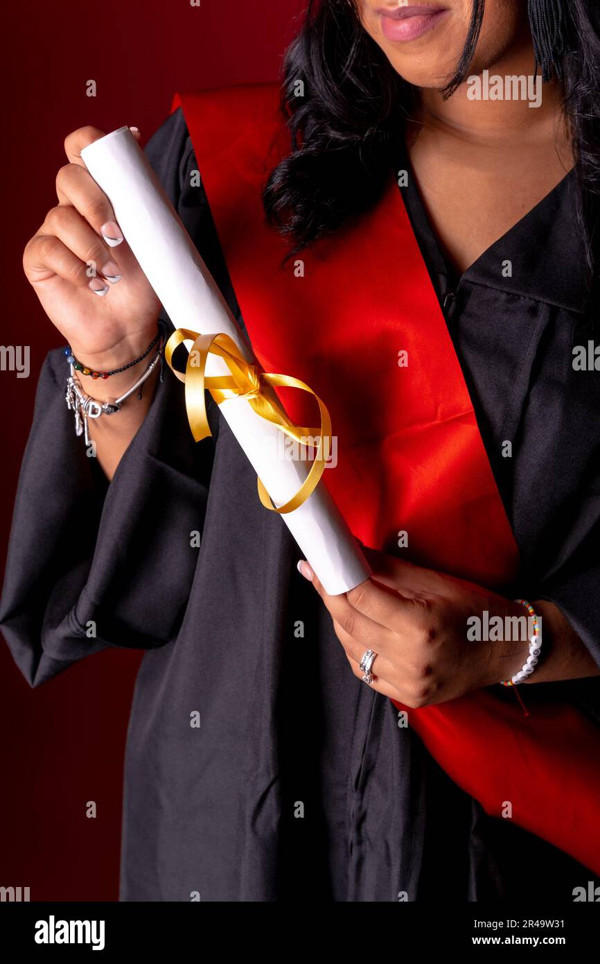 A young female graduate standing proudly in her academic regalia with ...