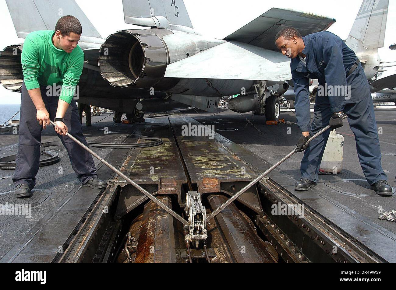 US Navy Airman perform maintenance on a steam-powered catapult aboard ...