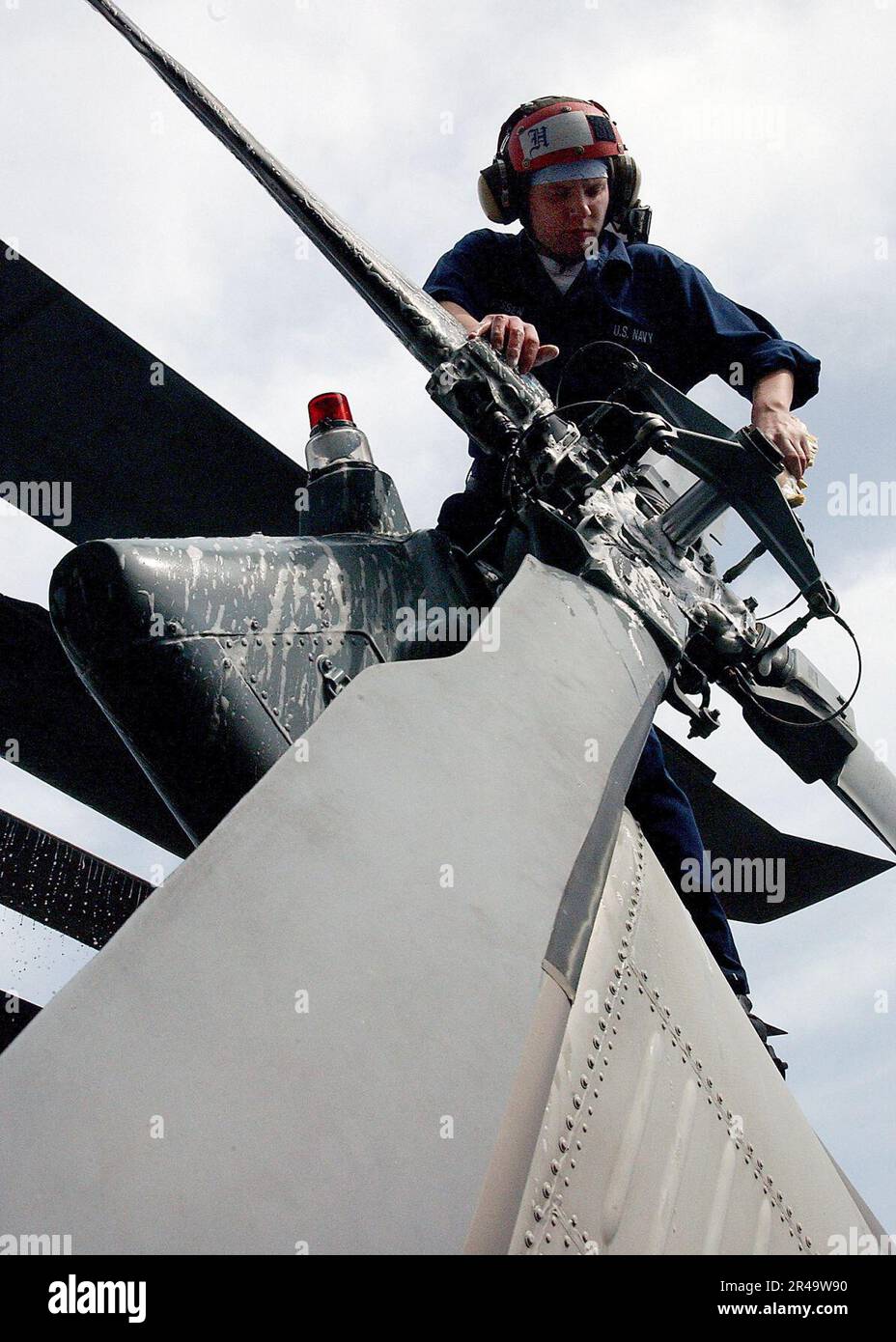 US Navy Aviation Ordnanceman Airman scrubs the rotors on an HH-60H ...