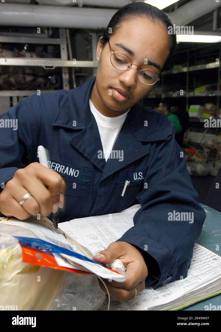 US Navy Storekeeper logs ordered parts in the stock control room aboard ...