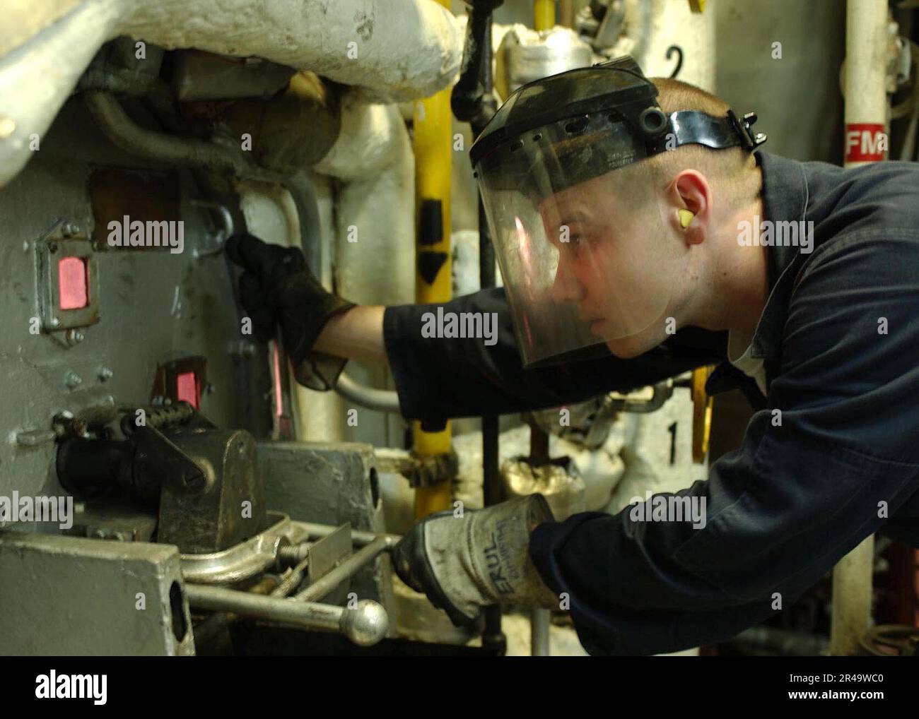 US Navy Fireman checks a burner fire, in a boiler down in the ...