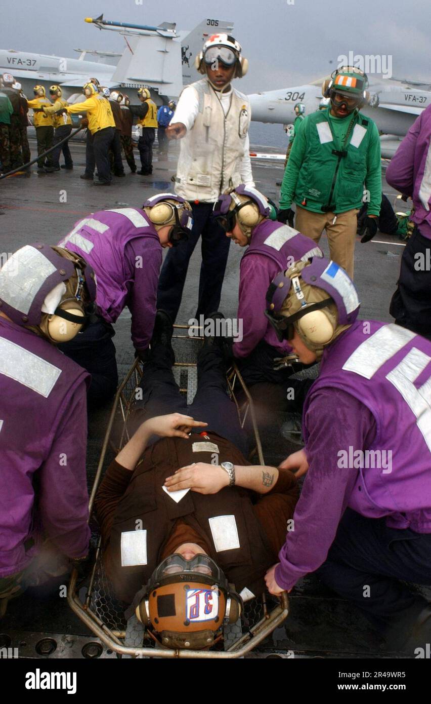 US Navy Flight deck personnel lift a patient in a stokes stretcher off ...