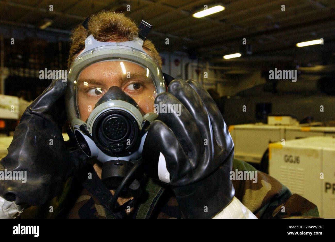 US Navy Hull Maintenance Technician relaxes his gas mask during a ...