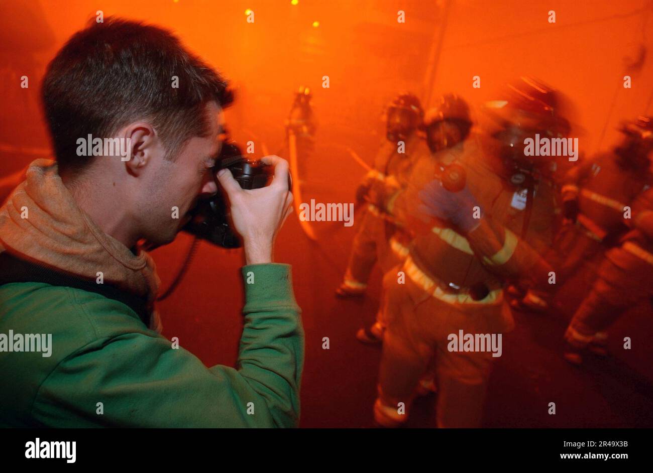 US Navy Photographer's Mate photographs a fire fighting hose team ...