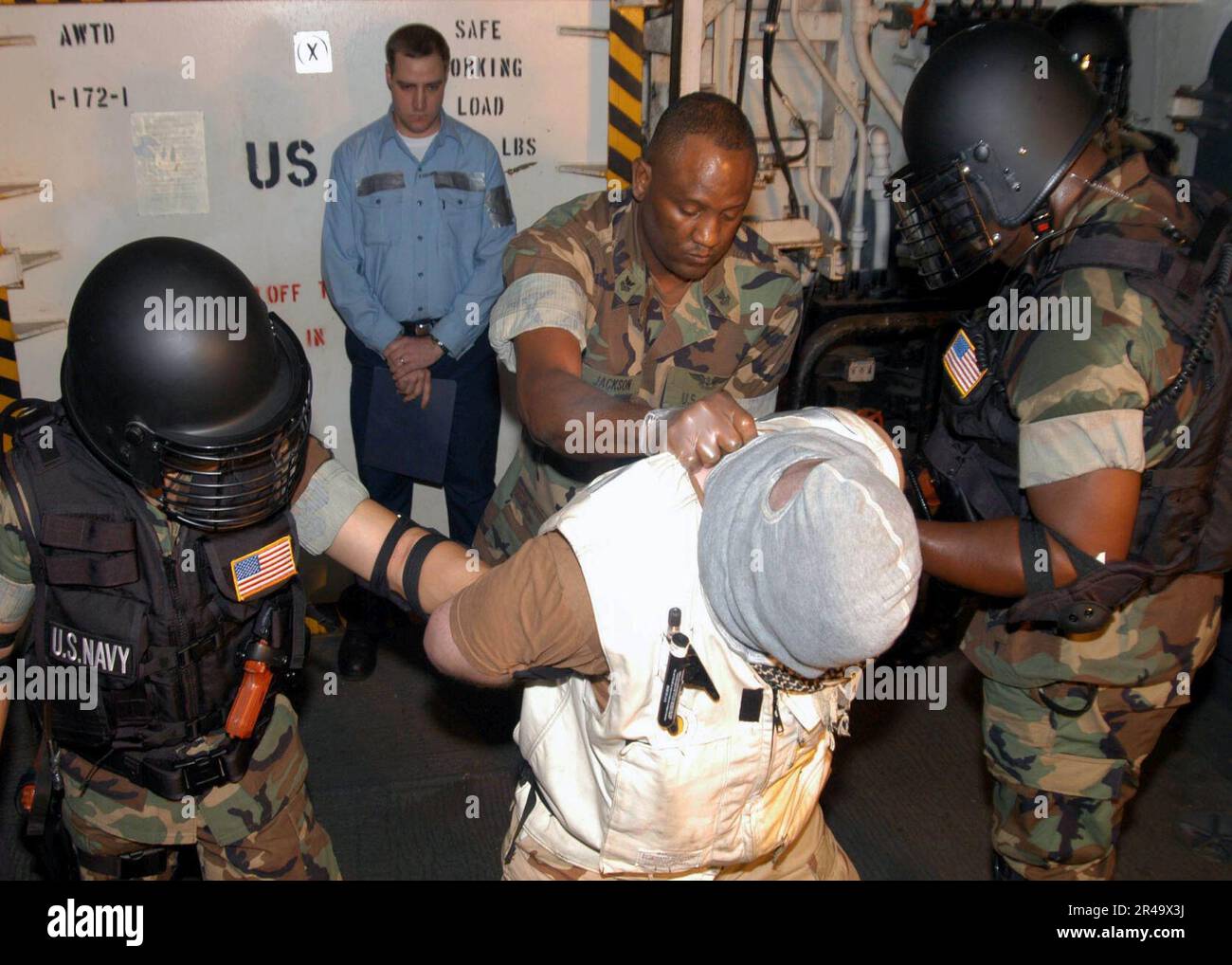 US Navy Master-at-Arms 1st Class center, performs a search on a Sailor ...