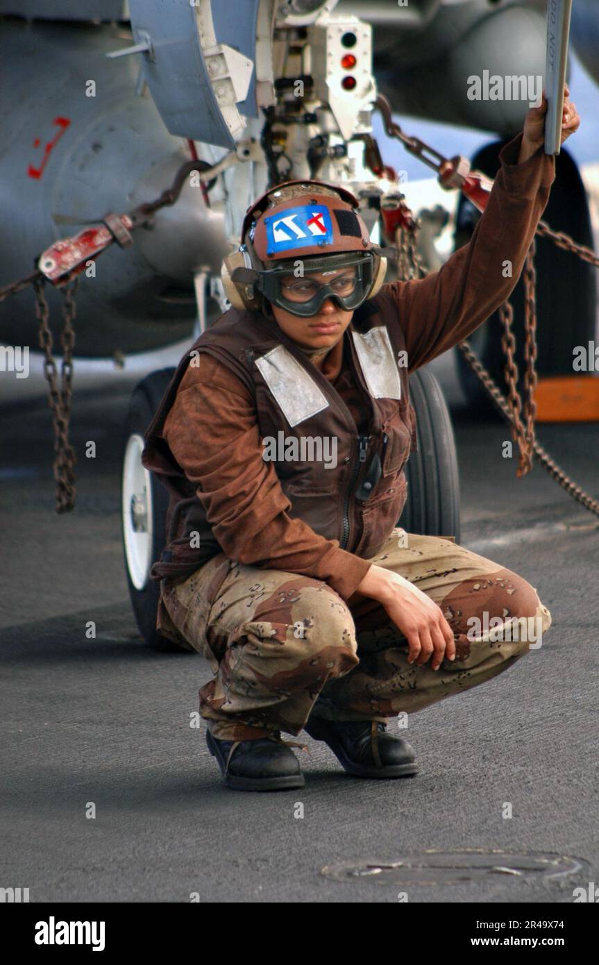US Navy Airman crouches under the nose of an F-A-18F Super Hornet Stock ...
