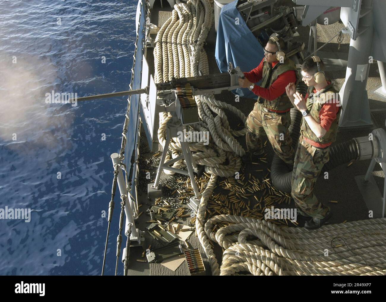 US Navy Aviation Ordnanceman fires .50 cal machine gun at a floating ...