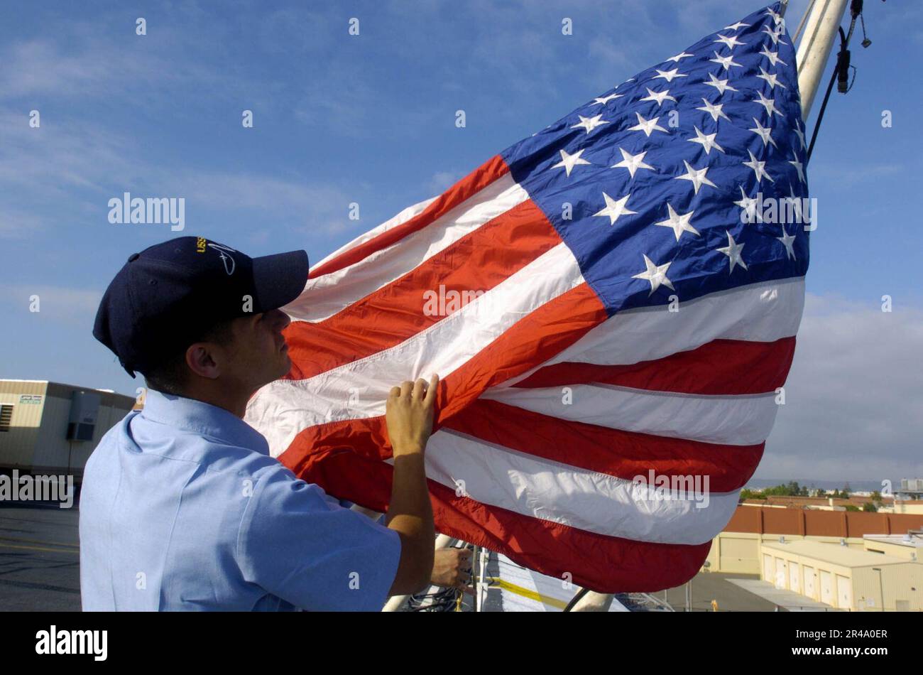 US Navy Seaman strikes the colors during morning colors on the flight ...
