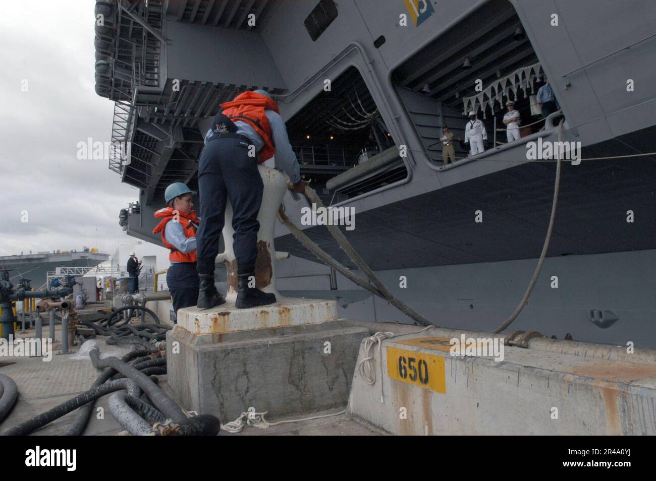 US Navy Line handlers remove mooring lines from the bollards on the ...
