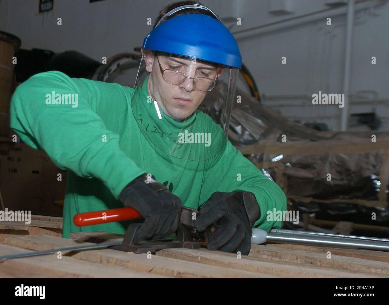 US Navy Storekeeper 3rd Class places metal bands on wooden pallets ...