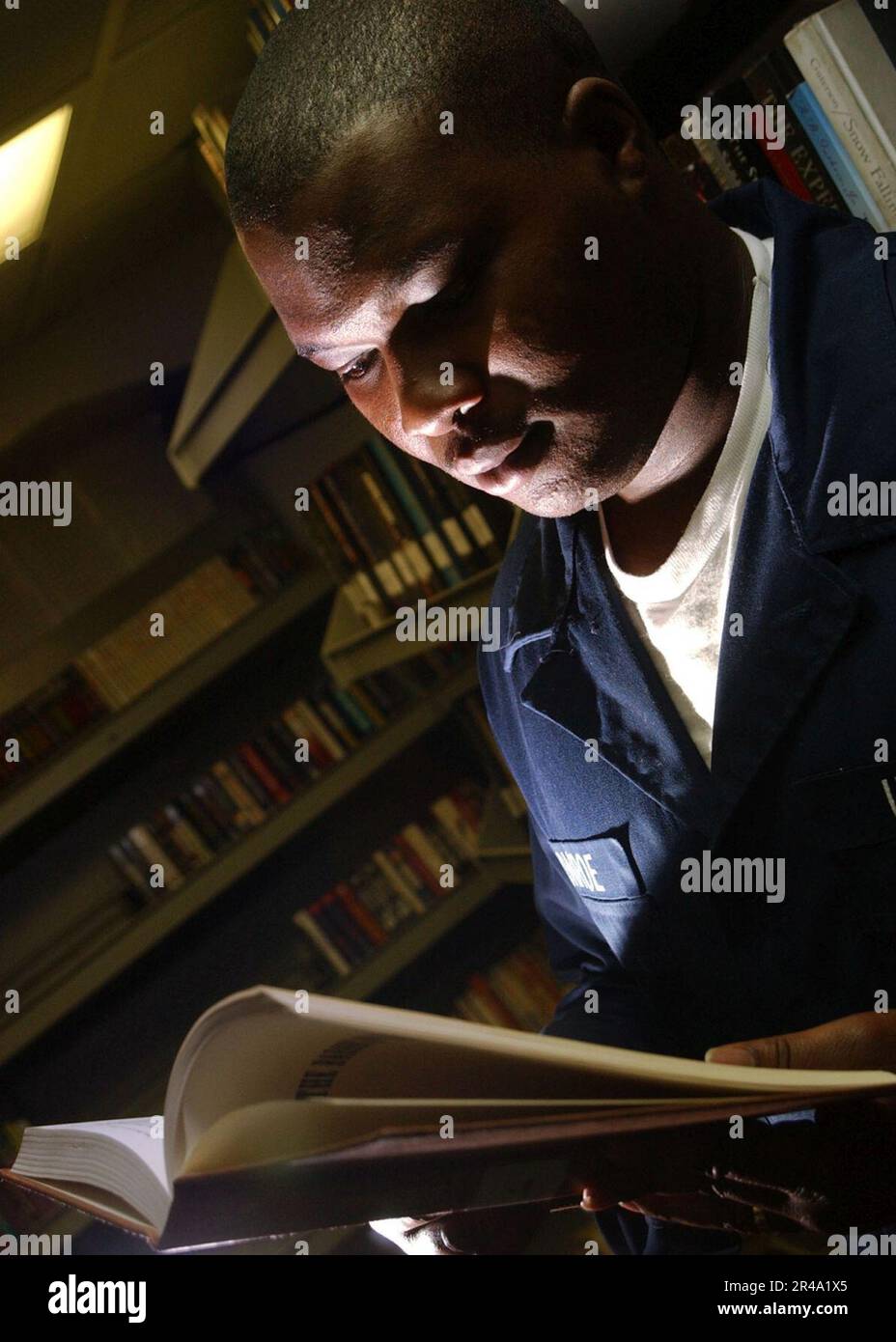 US Navy ireman selects a book to read from the library aboard USS Harry ...