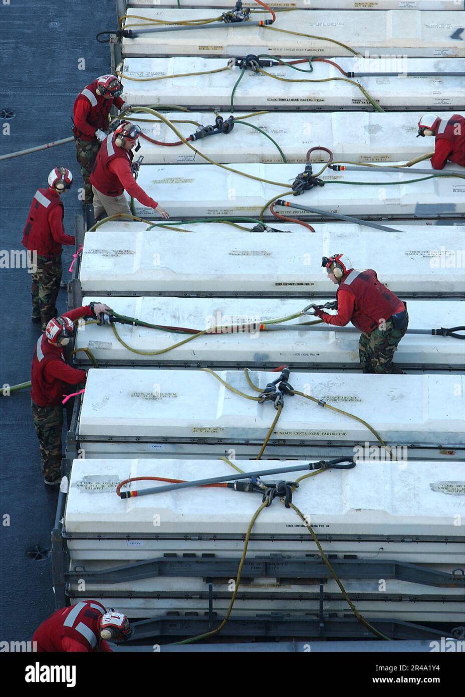 US Navy Weapons Department crew members receive ordnance from the ...