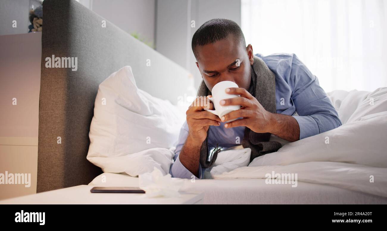 Sick Man Sitting On Bed Holding Cup Of Tea Stock Photo - Alamy